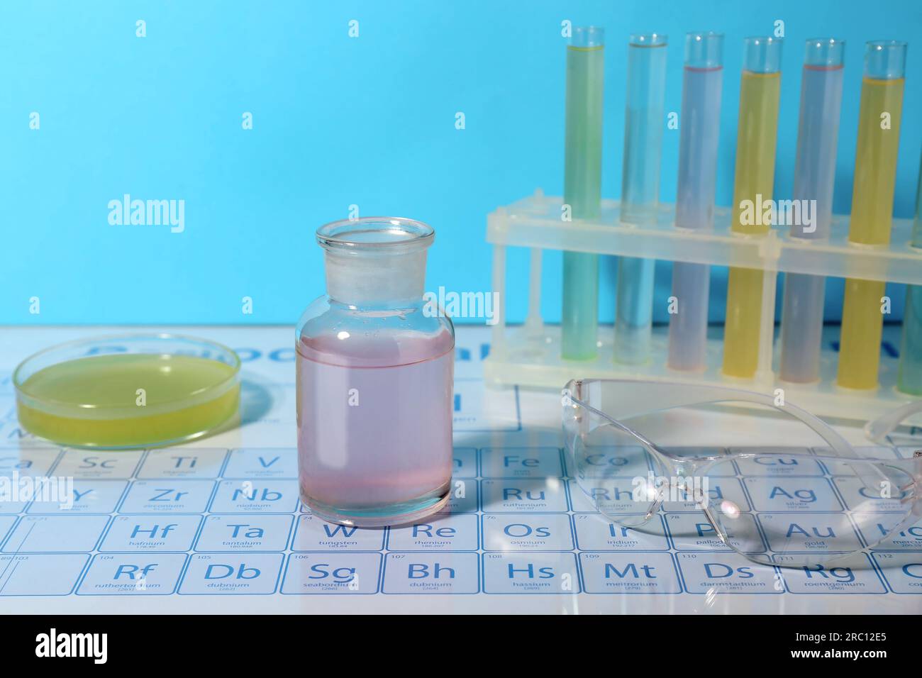 Safety glasses, flask, petri dish and test tubes with different liquids ...