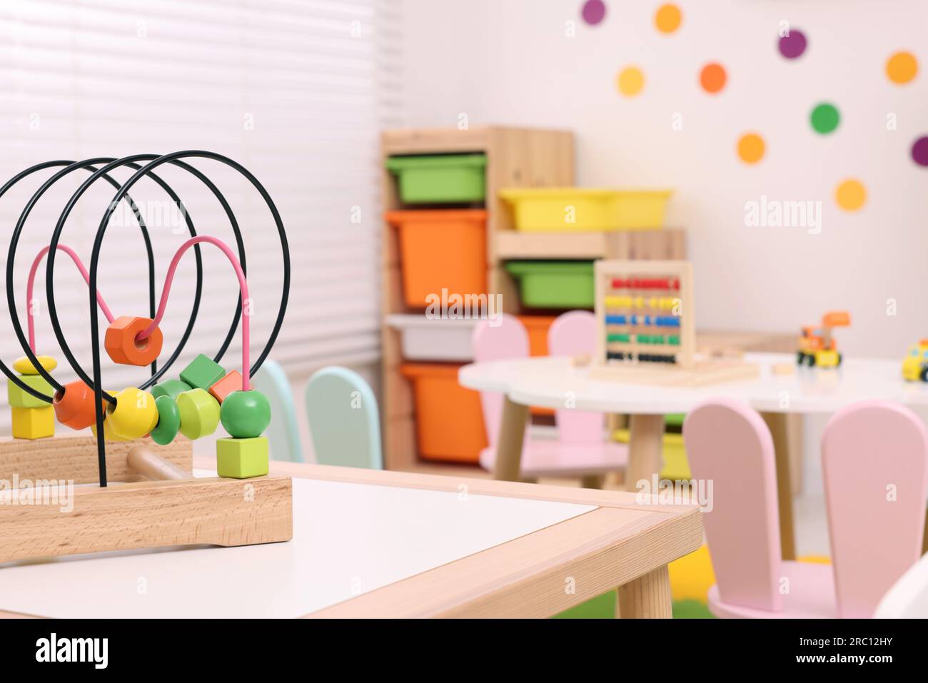 Toy bead maze on wooden table in playroom, space for text. Kindergarten ...
