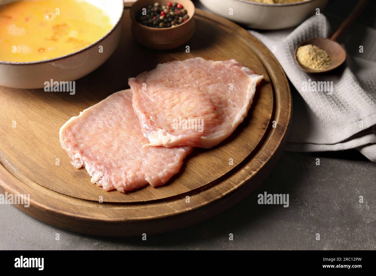 Cooking schnitzel. Raw pork slices and other ingredients on grey table ...