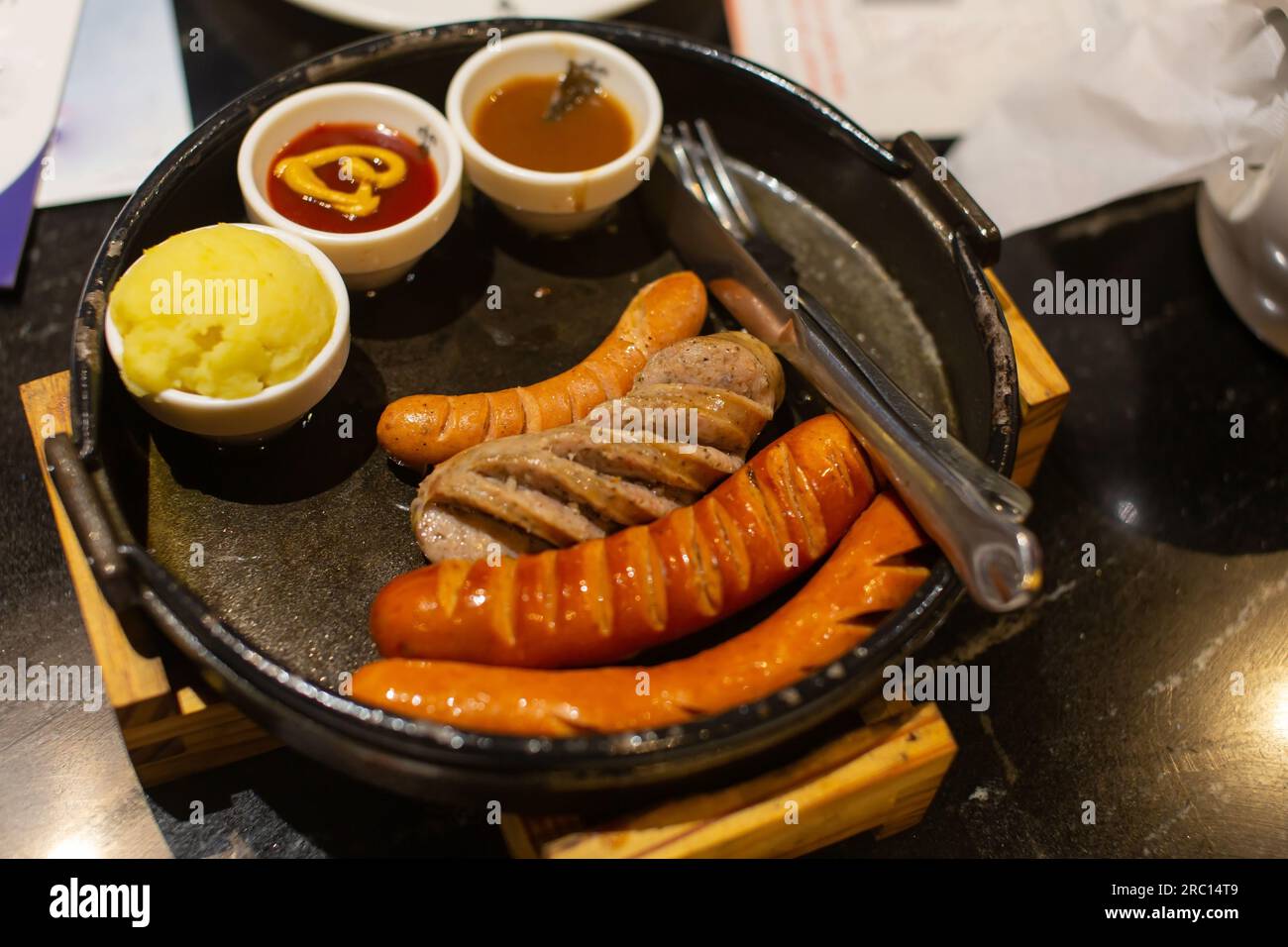 Barbecue sausage and side dish sauce on plate on black stone background ...