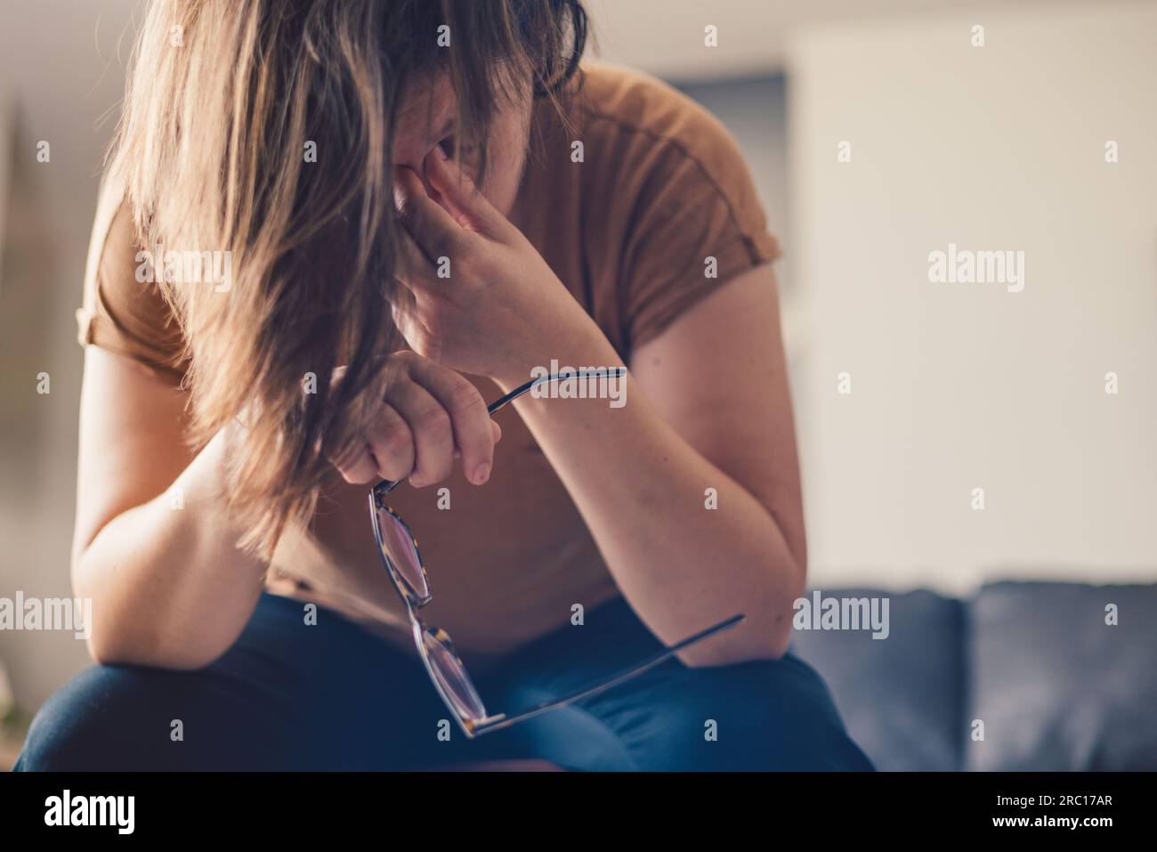 Young millennial mother at home with prescription glasses head down sad ...