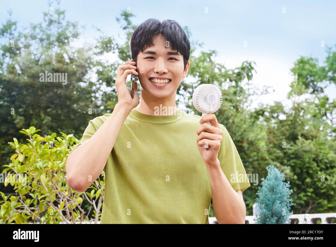 summer lifestyle, korean asian young man talking with electric fan ...