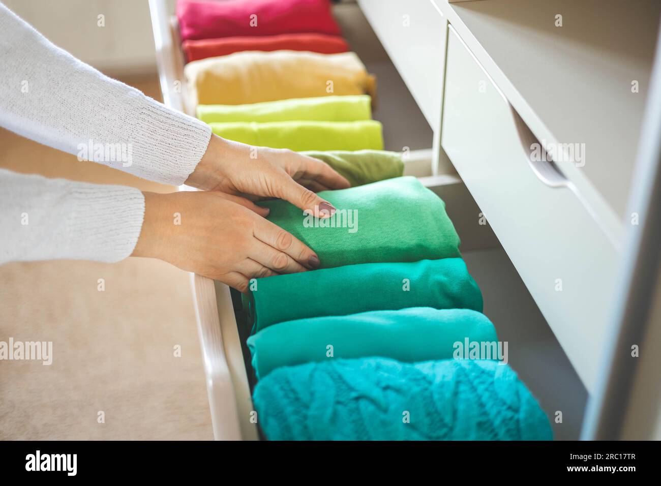 A lot of colorful clothes are neatly arranged in a wardrobe drawer. The ...