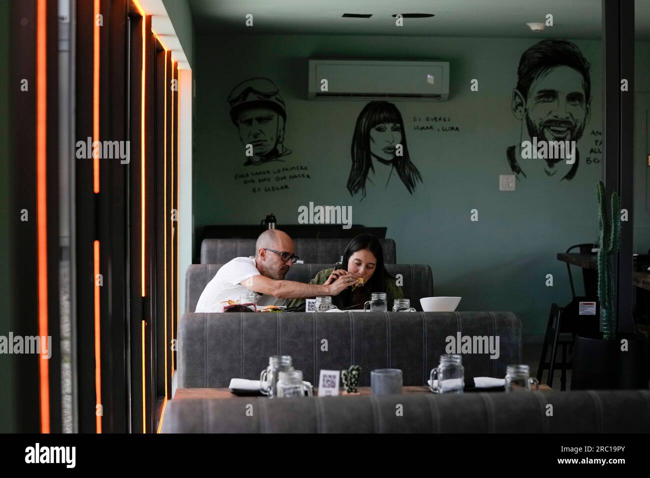 A couple eats near art depicting Argentine soccer player Lionel Messi ...