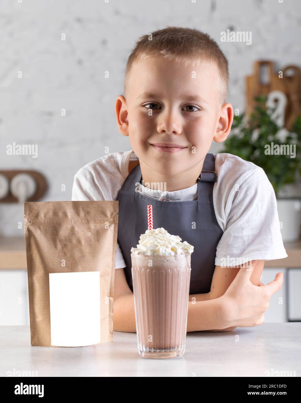A cute boy made a milkshake. The child is standing at the table with a ...