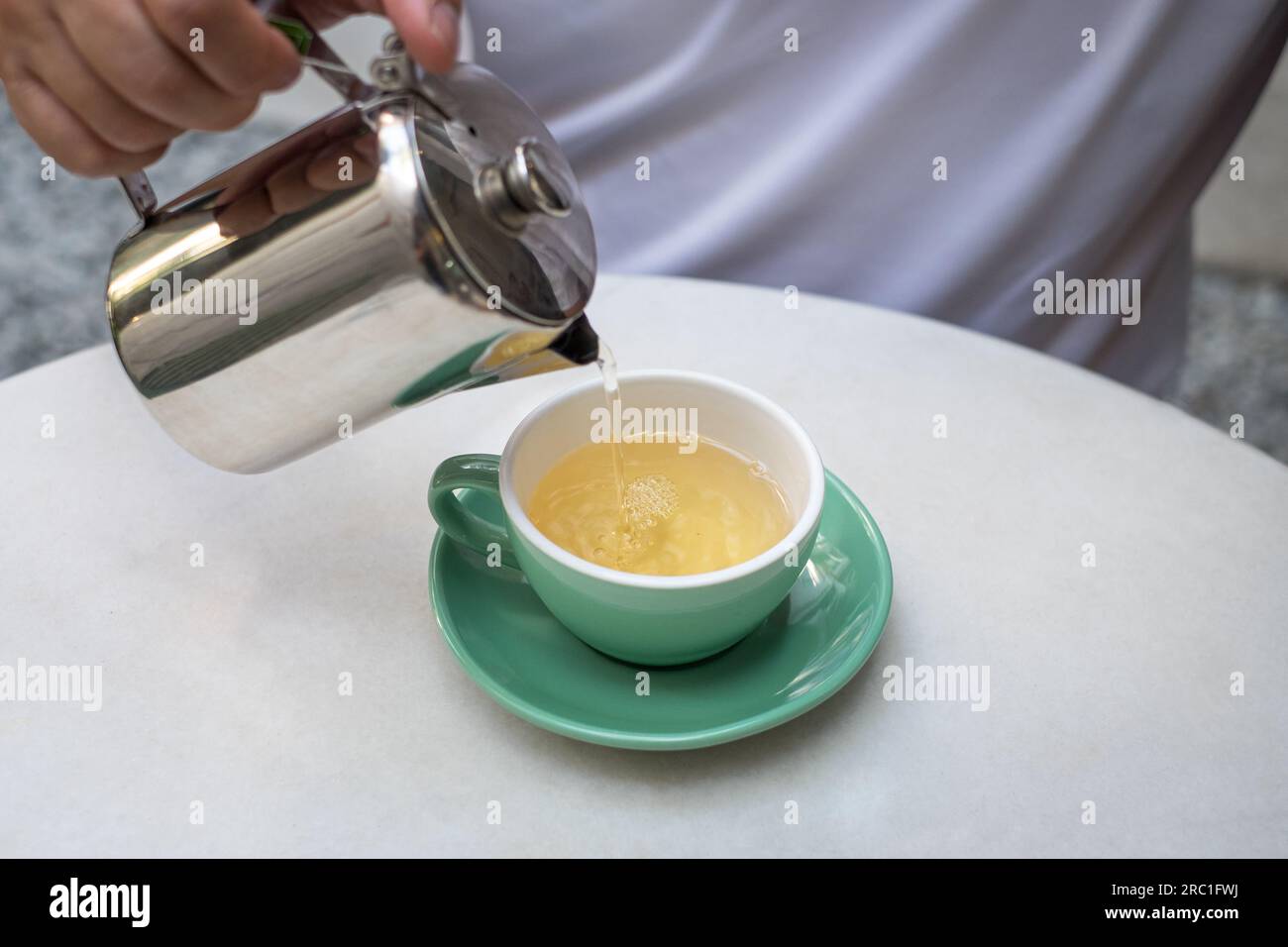Pouring hot tea from pot to cup. Time for tea break Stock Photo - Alamy