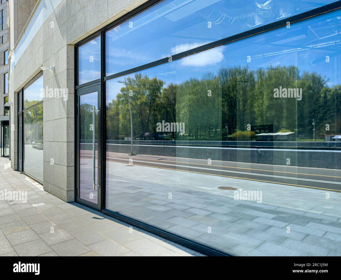 big blue windows of new office building with trees reflections. detail ...
