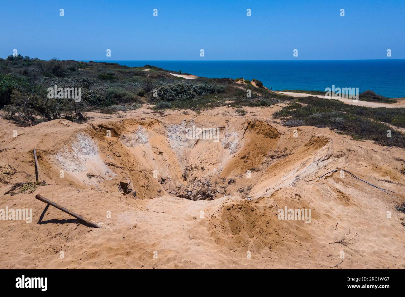A massive crater sits in the sandy earth from explosions in the ...