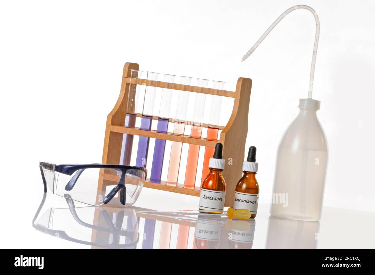 Rack with test tubes with coloured substances, plastic bottle, glasses ...