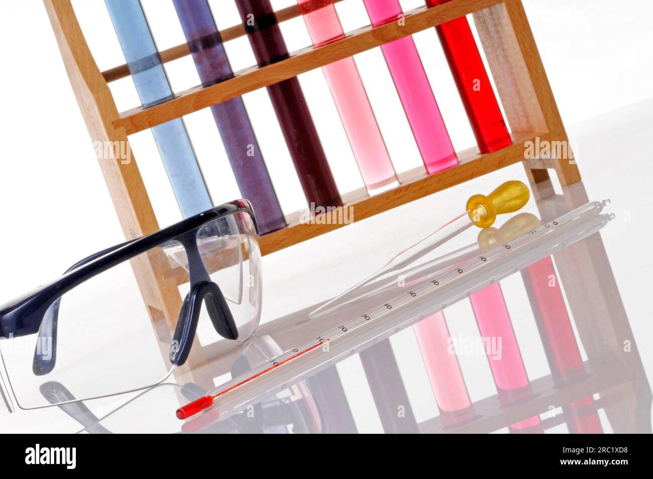Rack with test tubes with coloured substances, glasses, pipette ...