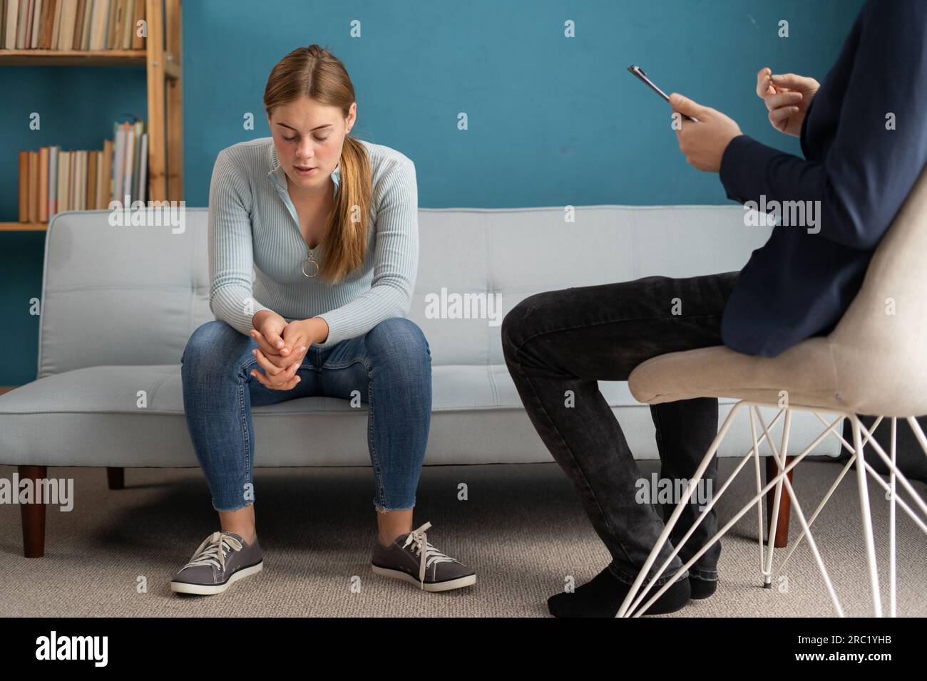 Psychologist taking notes during therapy session with sad young woman ...