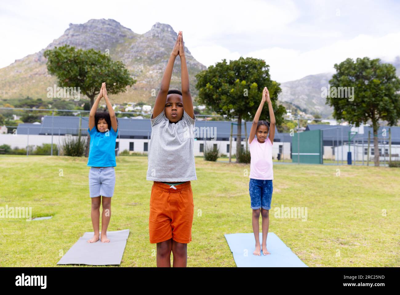 Happy african american schoolchildren doing yoga and meditating on ...