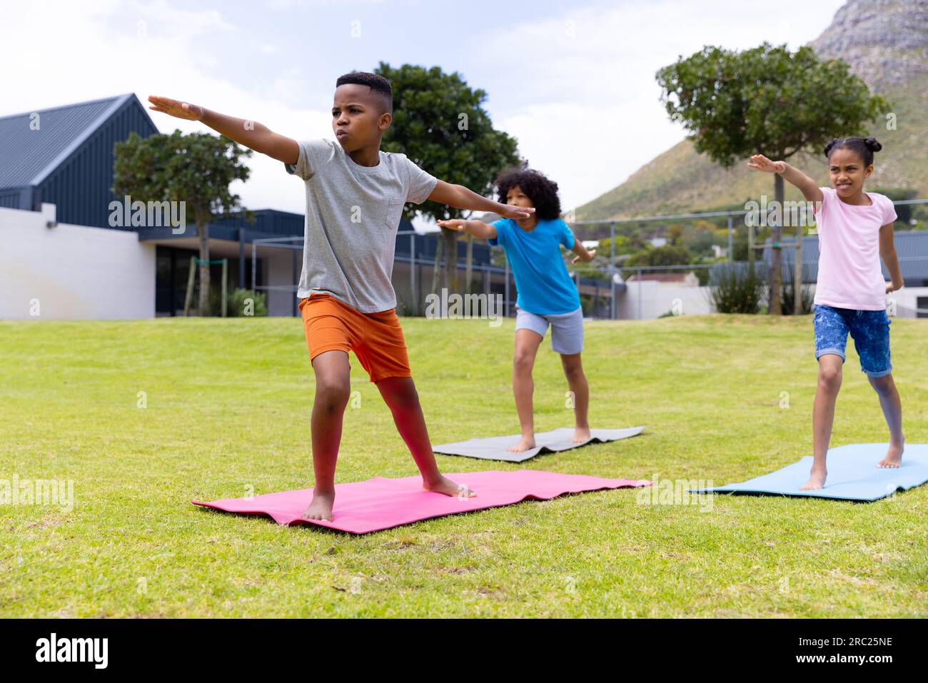Happy african american schoolchildren doing yoga and stretching on ...
