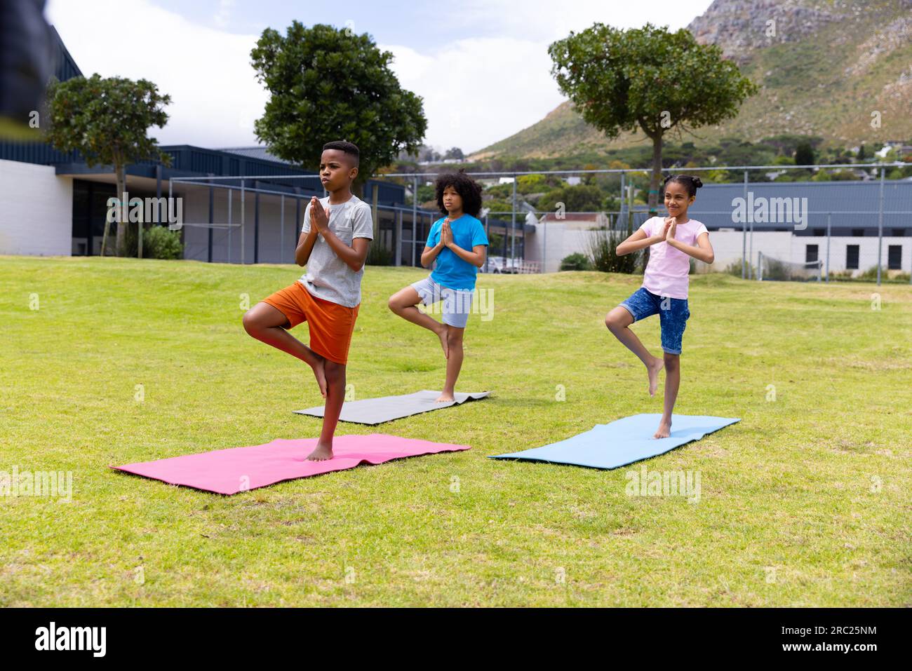 Happy african american schoolchildren doing yoga and meditating on ...