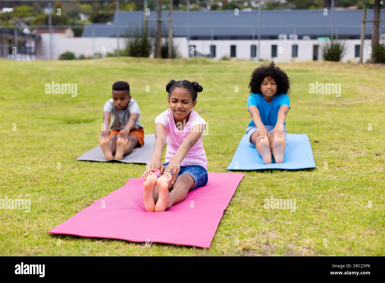 Happy african american schoolchildren doing yoga and stretching on ...