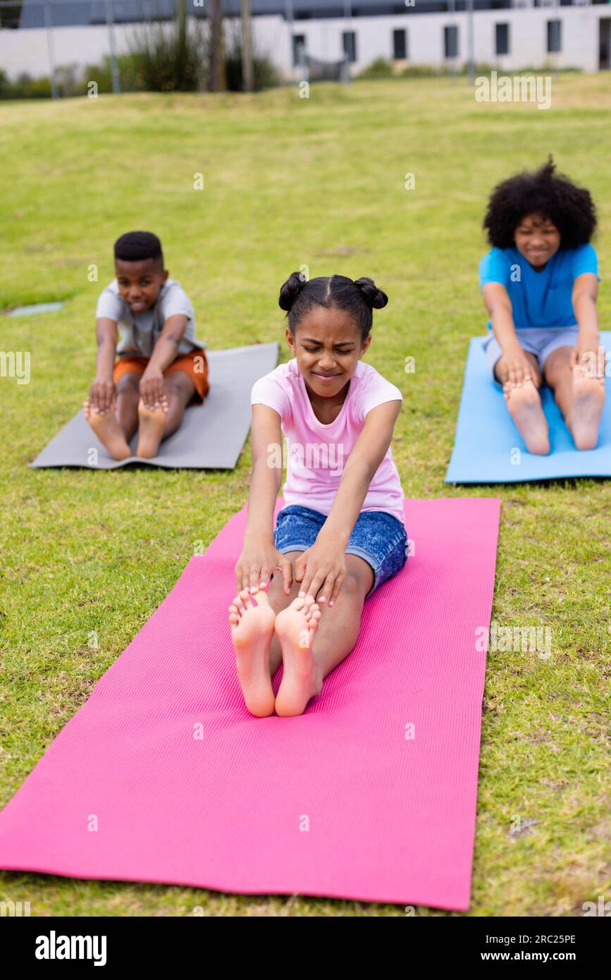 Happy african american schoolchildren doing yoga and stretching on ...