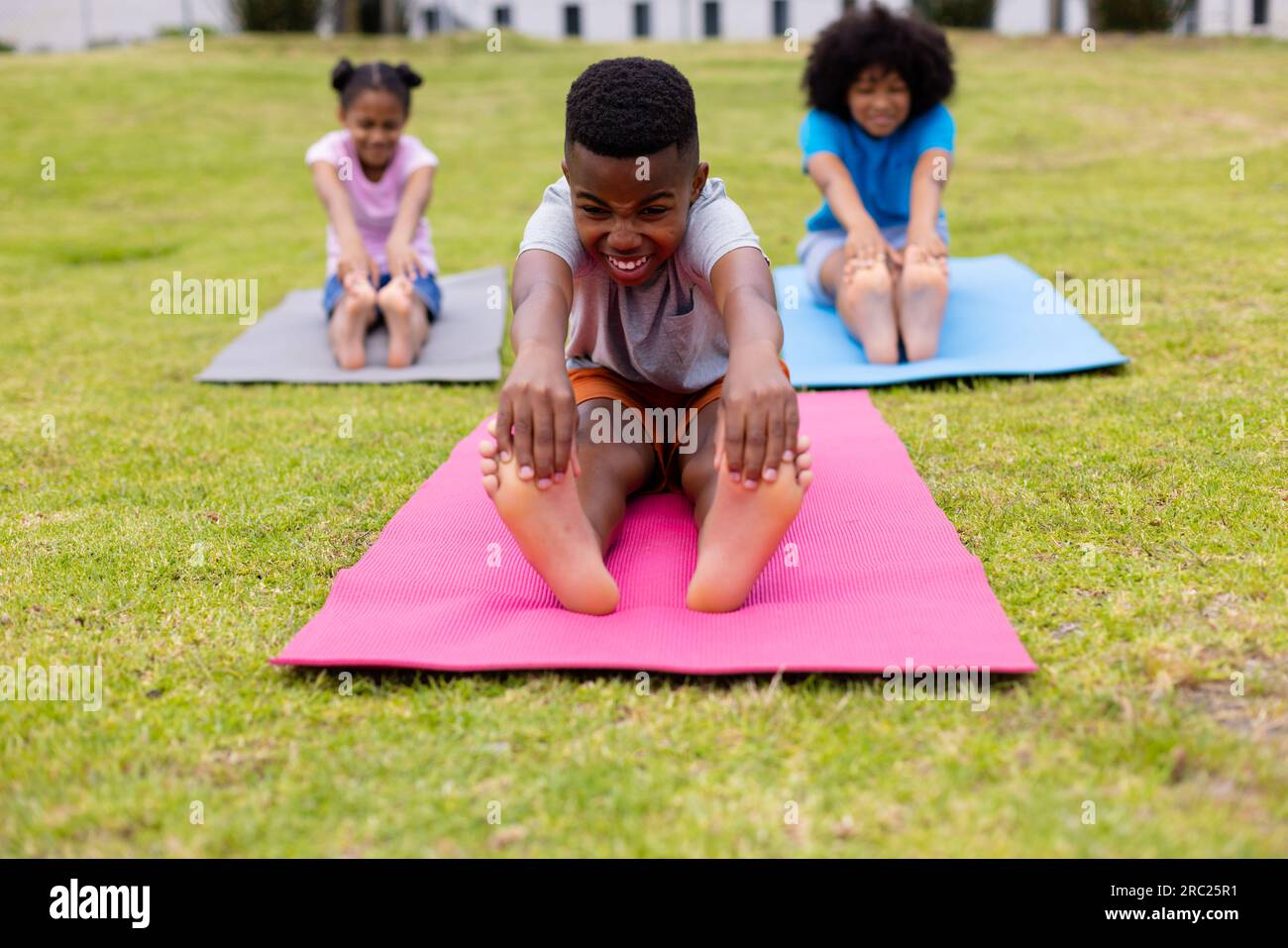 Happy african american schoolchildren doing yoga and stretching on ...