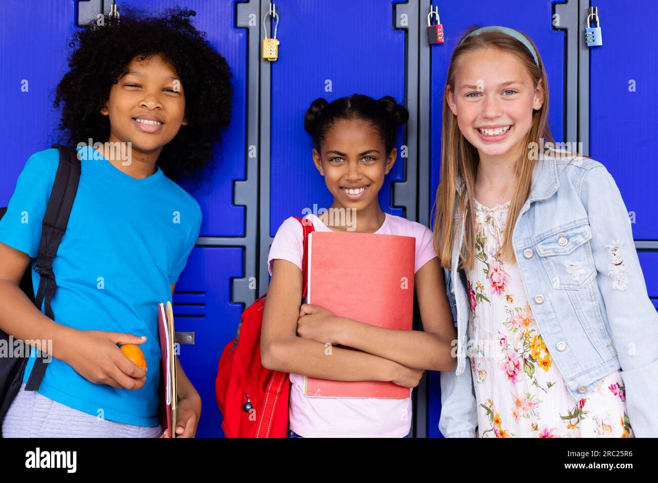 Portrait of happy diverse schoolchildren standing next to lockers in ...