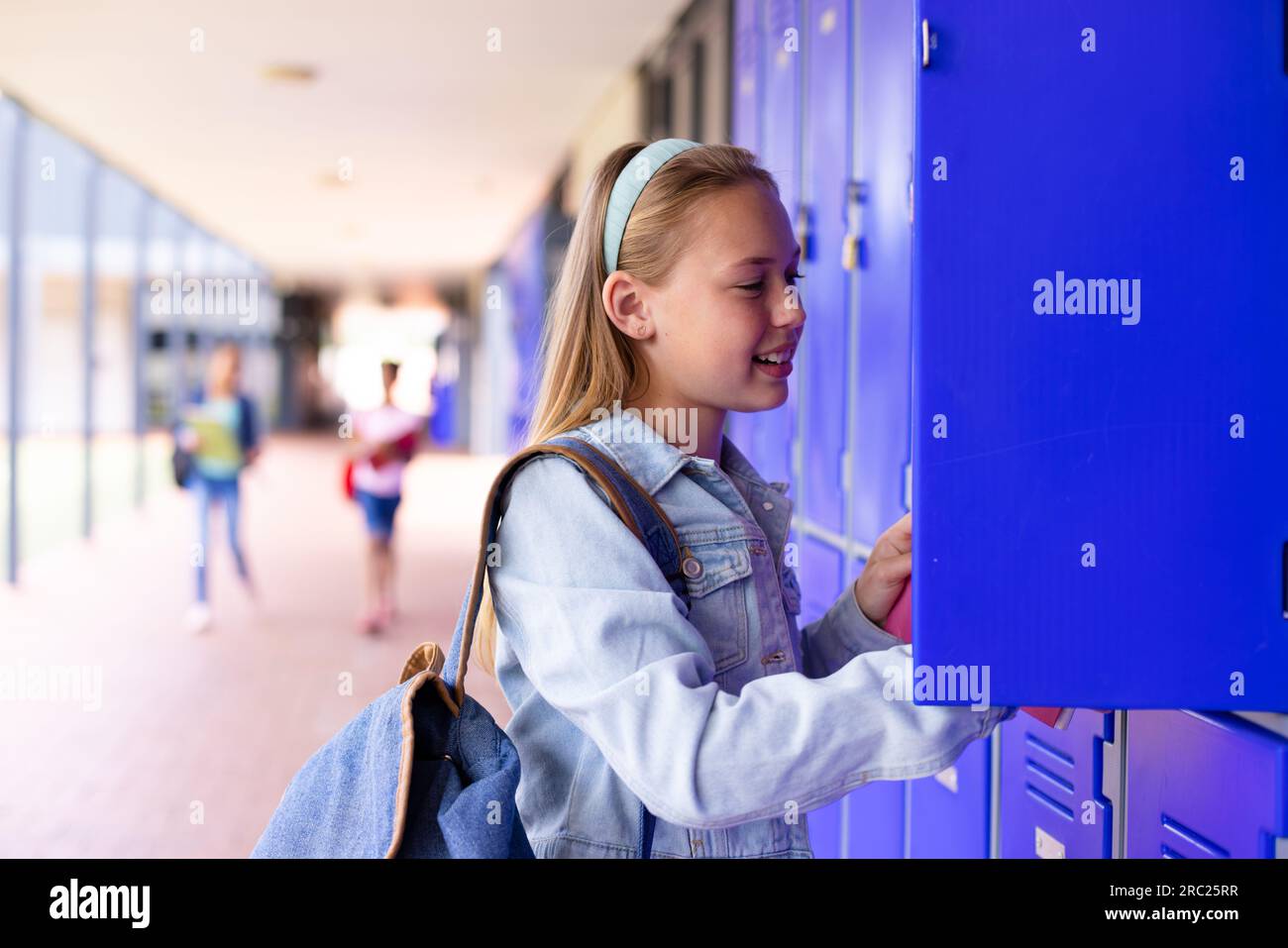 Happy caucasian schoolgirl standing next to lockers in corridor at ...