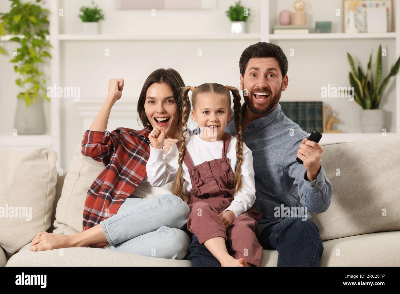 Happy family watching TV on sofa at home Stock Photo - Alamy