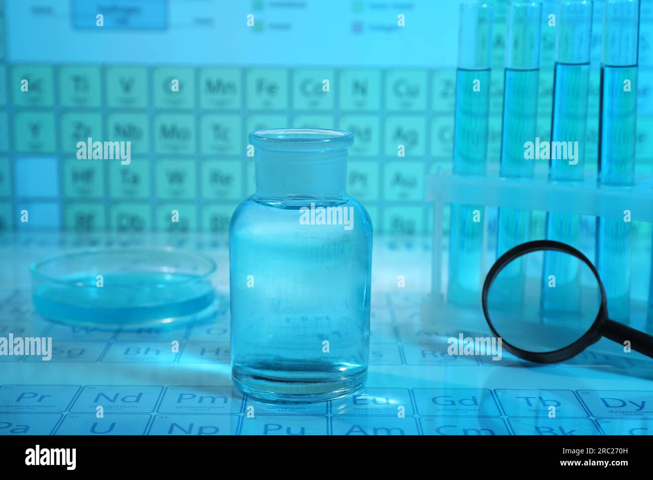 Laboratory glassware, petri dish and magnifying glass on periodic table ...