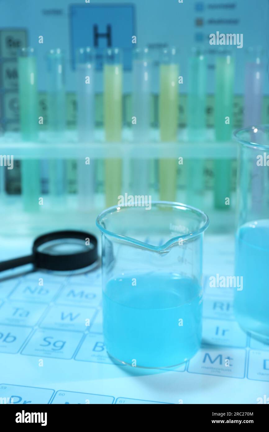 Beaker with liquid, test tubes and magnifying glass on periodic table ...