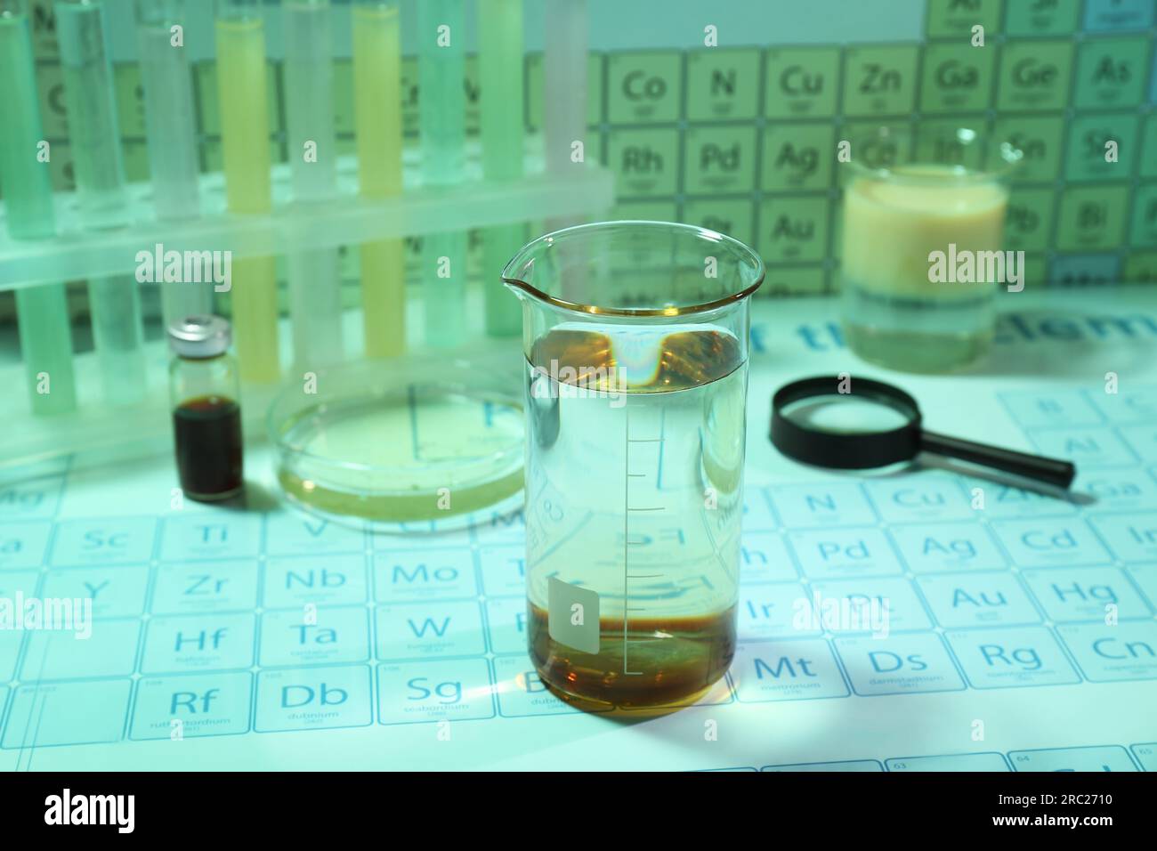 Beaker with liquid and laboratory equipment on periodic table of ...
