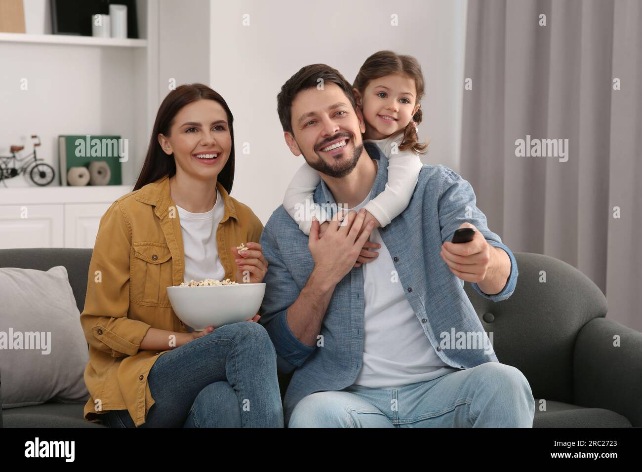 Happy family watching movie at home. Father changing TV channels with ...