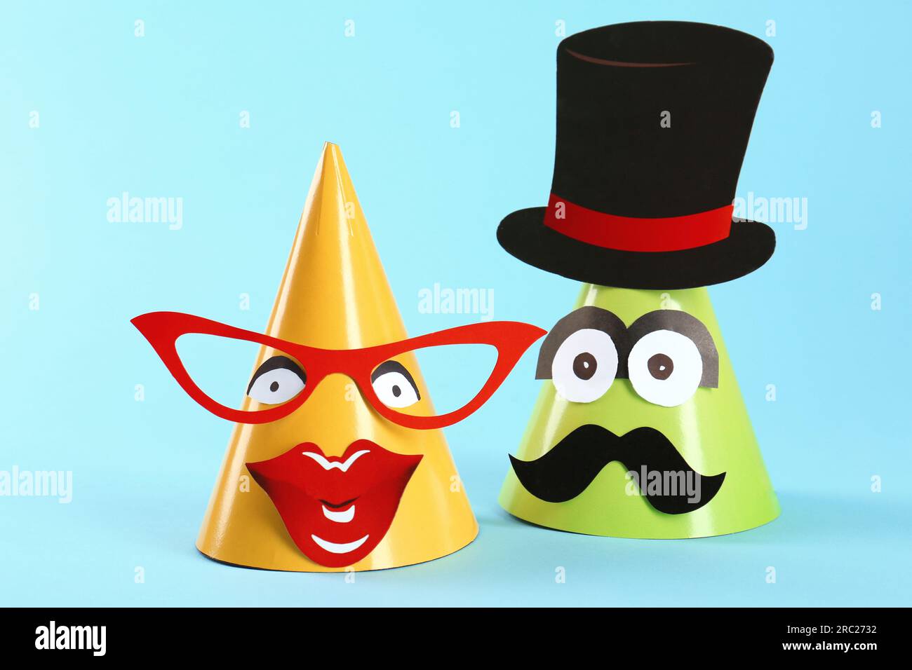 Handmade party hats with funny faces on light blue background Stock ...