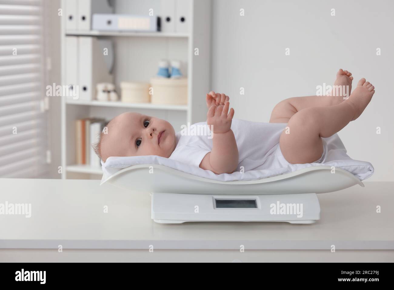 Cute little baby lying on scales in clinic Stock Photo - Alamy