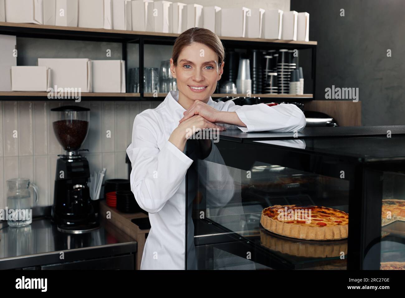 Professional baker near showcase with pastries in store Stock Photo - Alamy