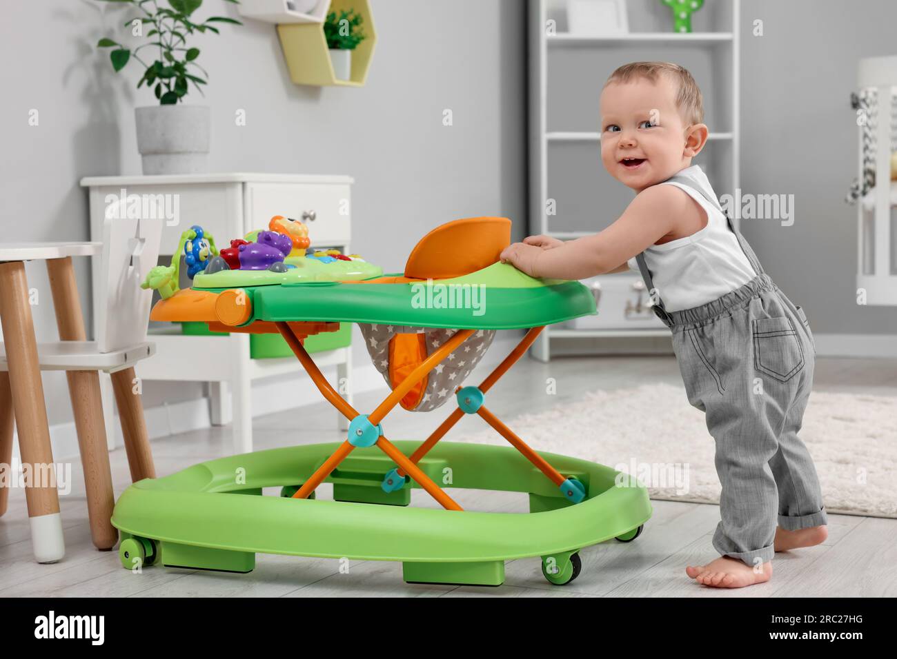 Cute baby making first steps with toy walker at home Stock Photo - Alamy