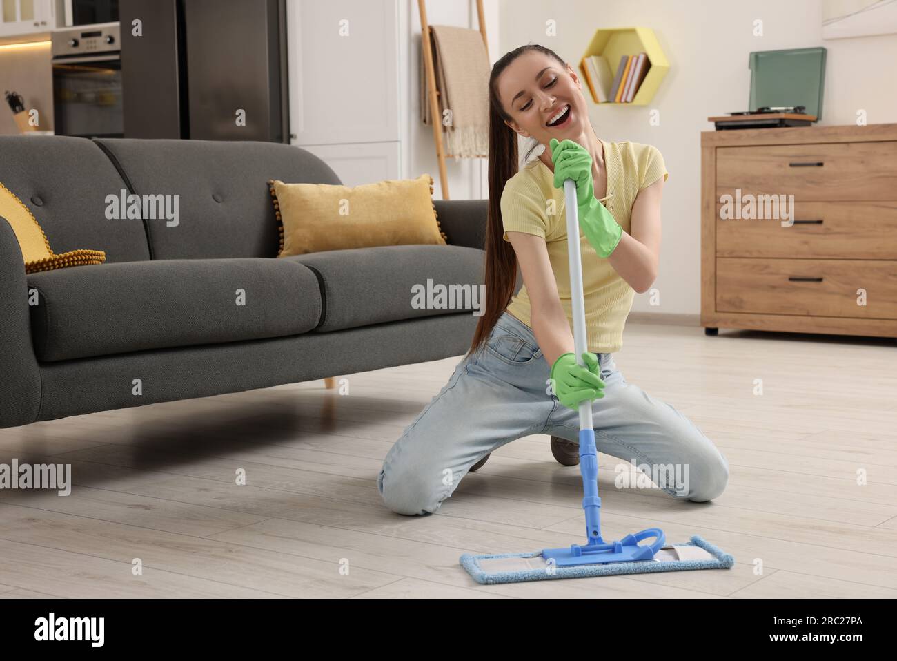 Spring cleaning. Young woman with mop singing while tidying up at home ...