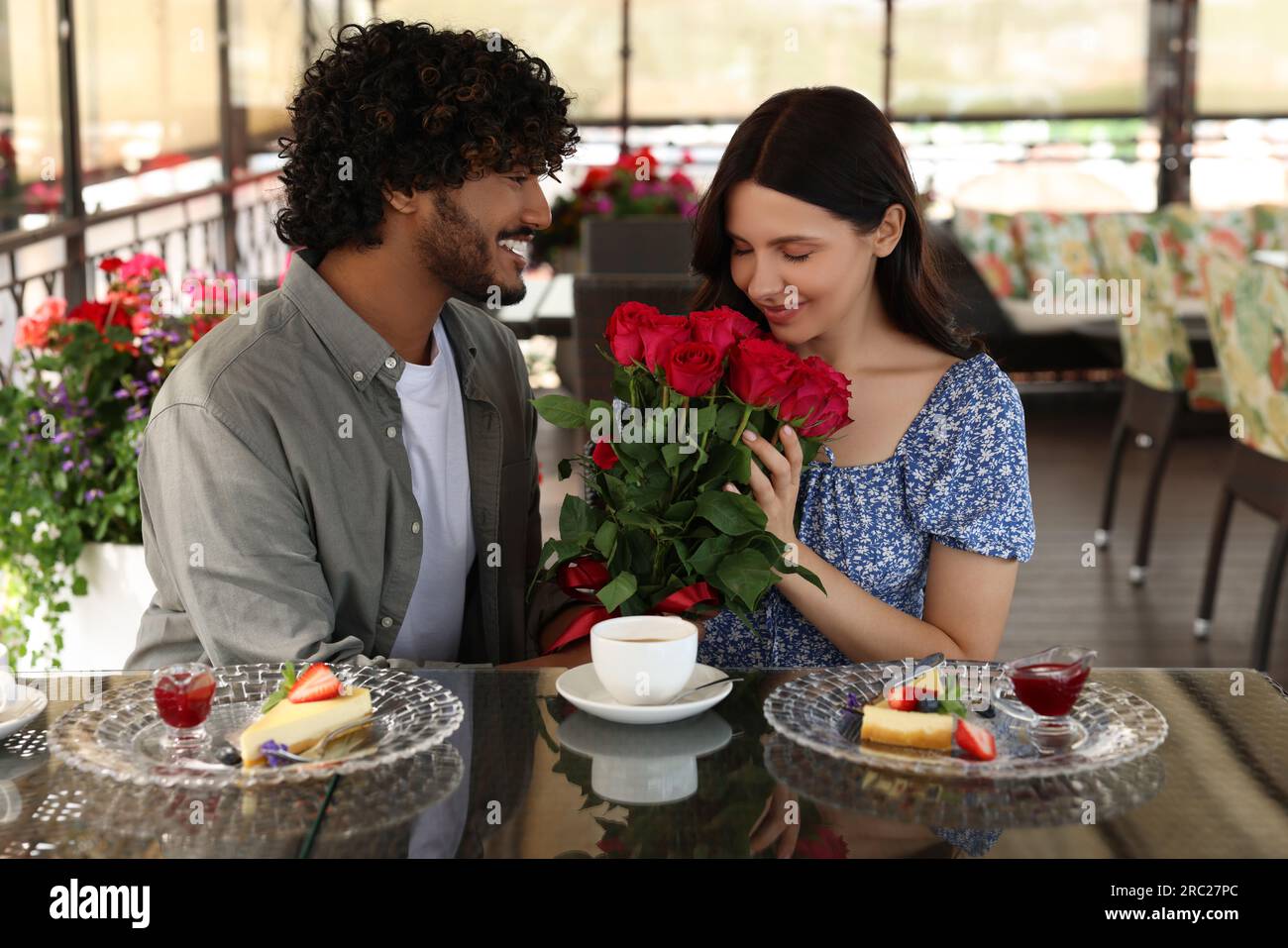 International dating. Handsome man presenting roses to his girlfriend ...