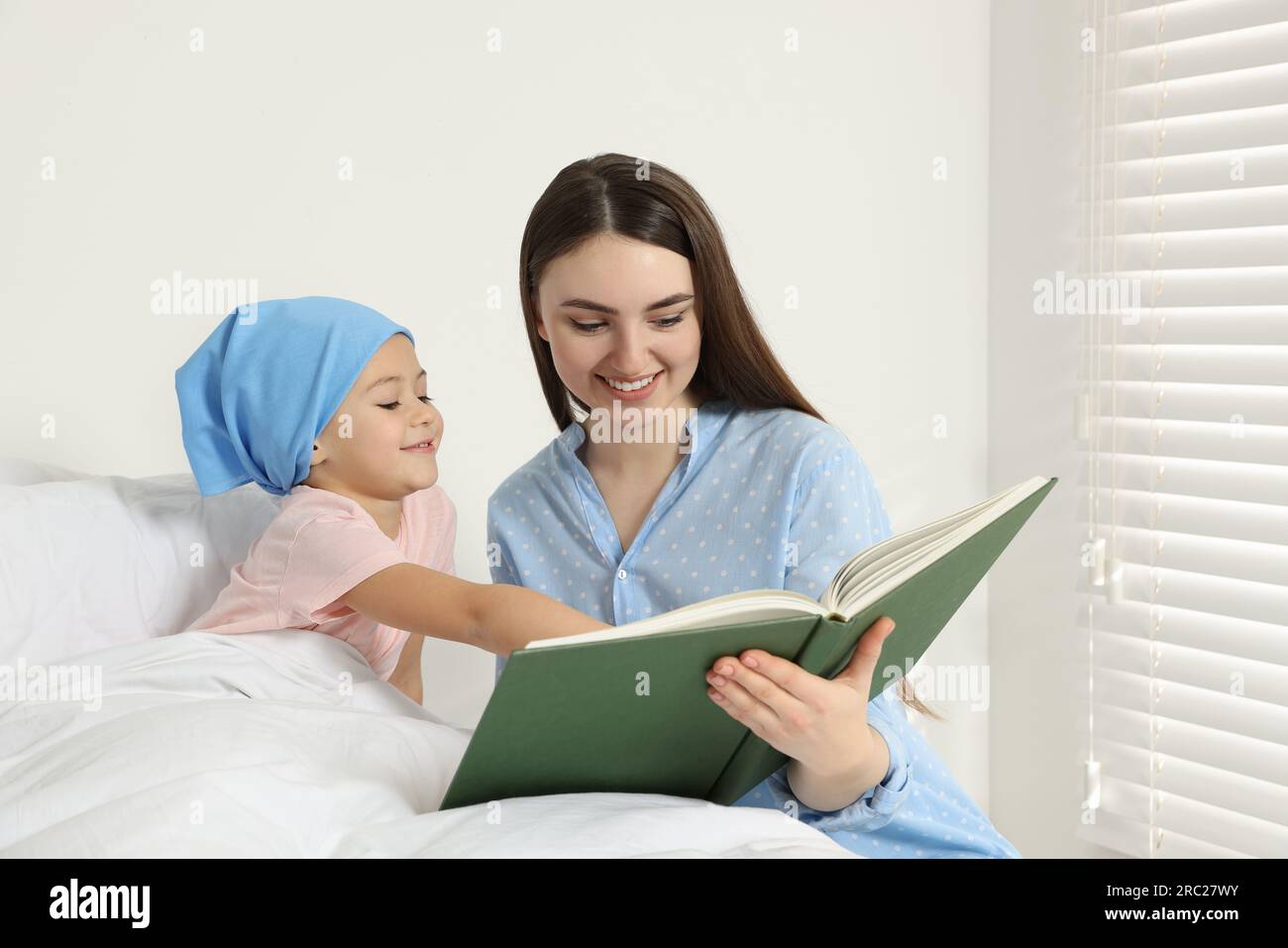 Childhood cancer. Mother and daughter reading book in hospital Stock ...