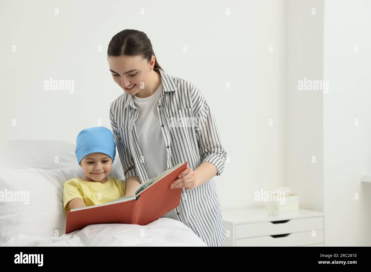 Childhood cancer. Mother and daughter reading book in hospital Stock ...