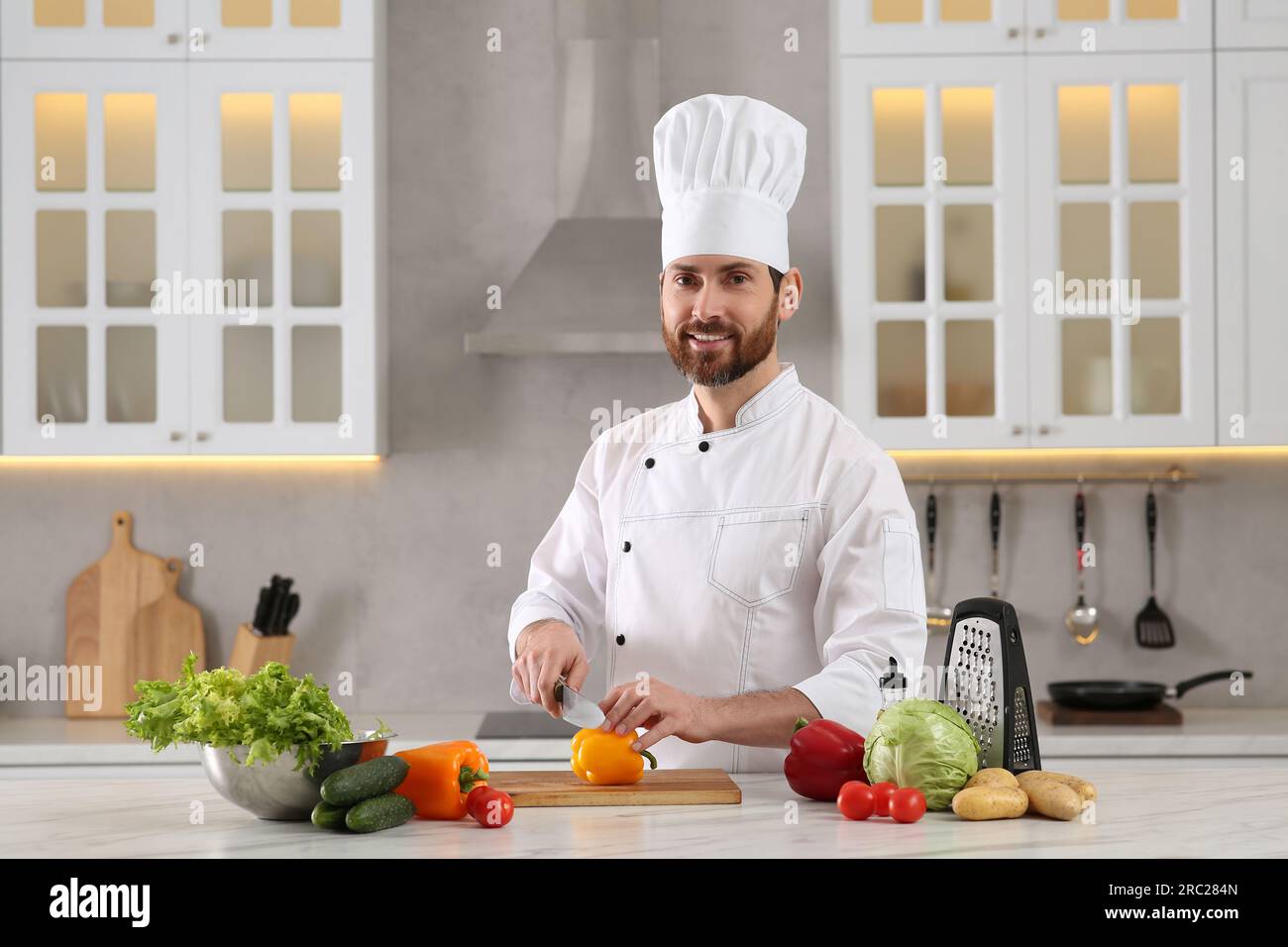 Chef cutting bell pepper at marble table in kitchen Stock Photo - Alamy