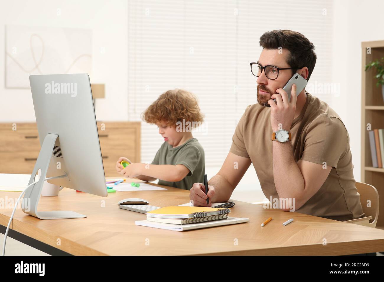 Man working remotely at home. Busy father talking on smartphone while ...