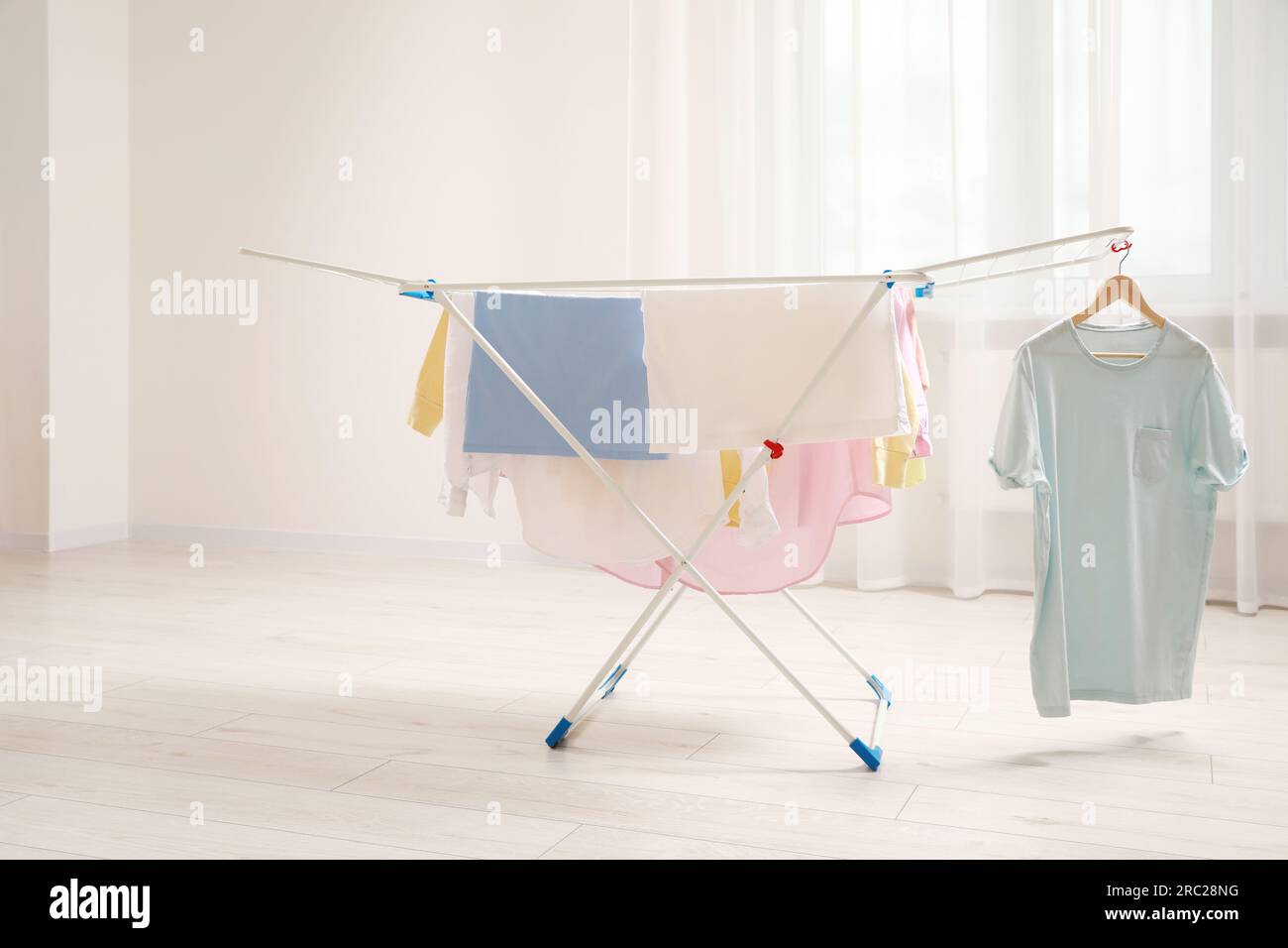 Clean laundry hanging on drying rack indoors Stock Photo - Alamy