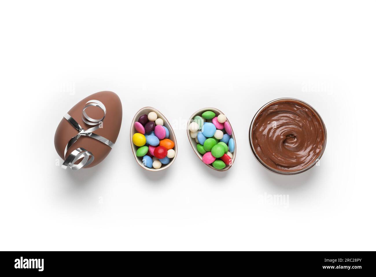 Delicious chocolate eggs, paste and colorful candies on white ...