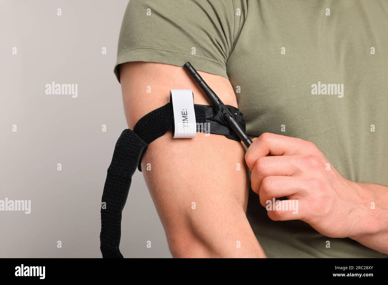 Soldier in military uniform applying medical tourniquet on arm against ...