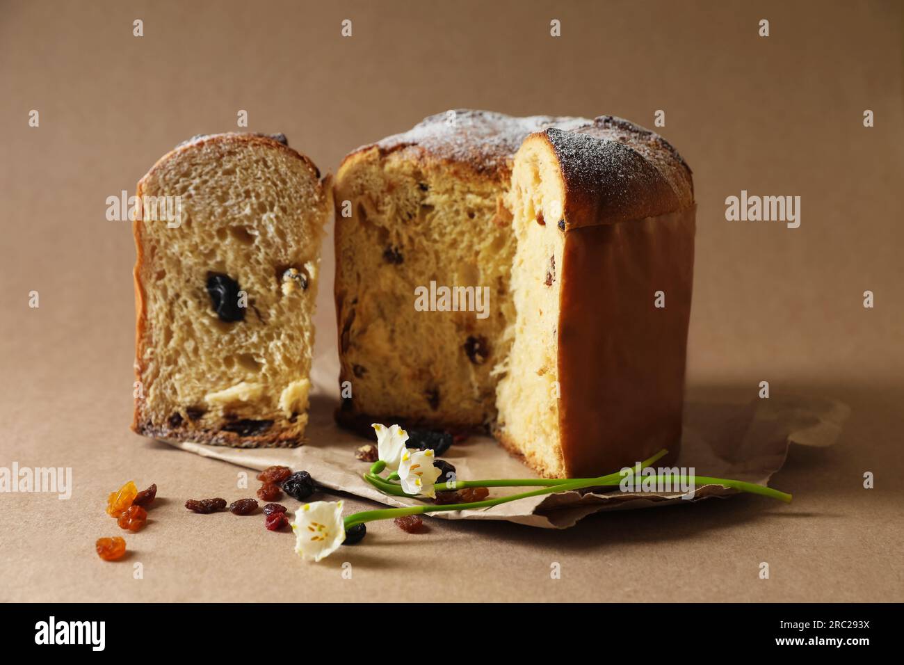 Delicious cut Panettone cake, raisins and beautiful flowers on light ...