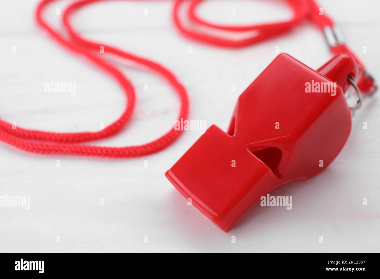 One red whistle with cord on white wooden table, closeup. Space for ...