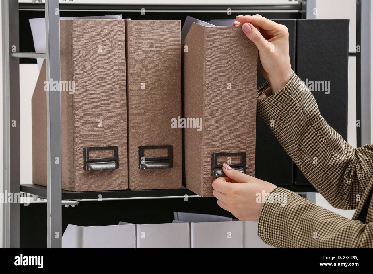 Woman taking folder with documents from shelf in office, closeup Stock ...