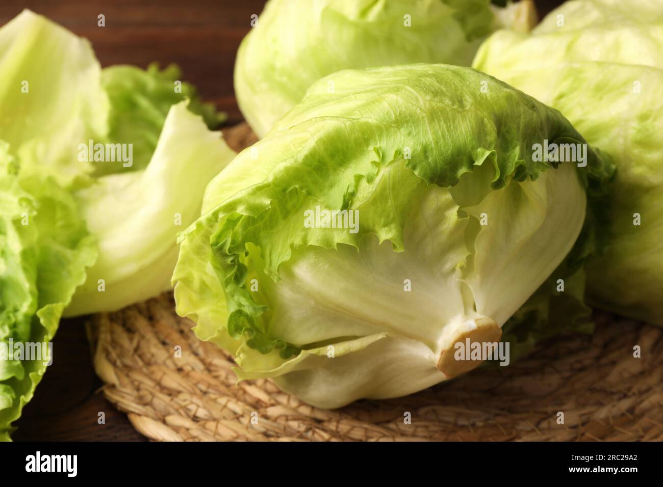 Fresh green iceberg lettuce heads and leaves on wicker mat, closeup ...