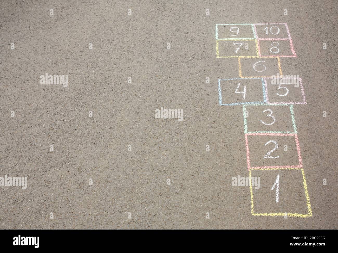 Hopscotch drawn with colorful chalk on asphalt outdoors. Space for text ...