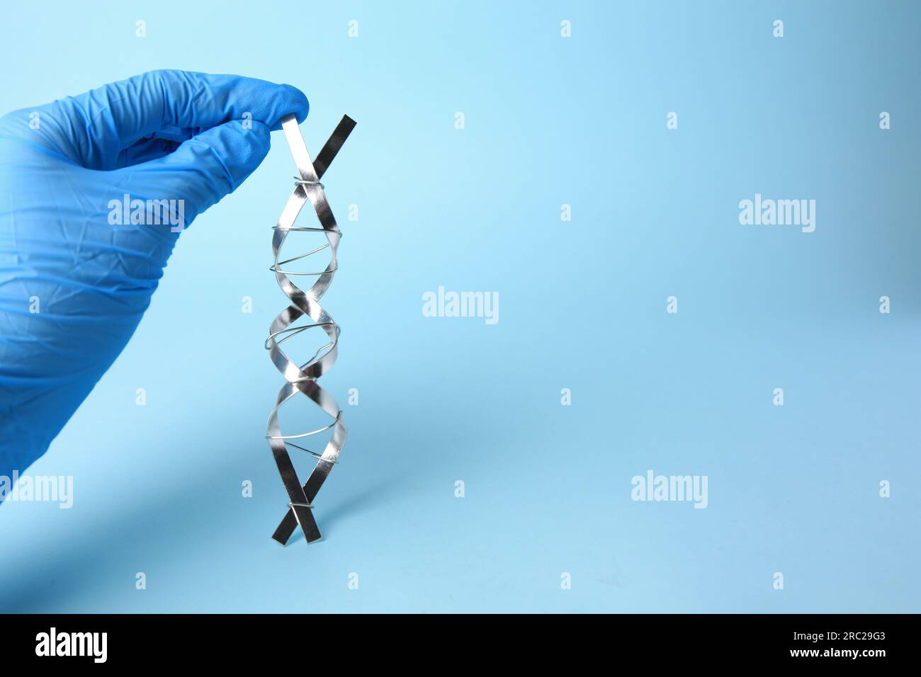 Scientist with DNA molecular chain model made of metal on light blue ...