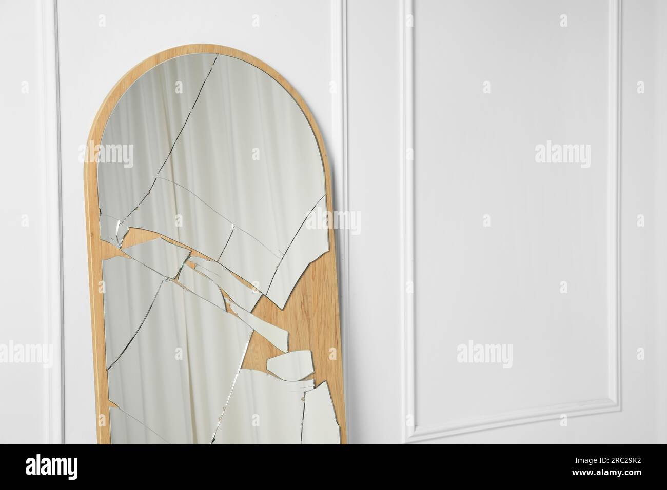 Broken mirror with many cracks near white wall. Space for text Stock ...