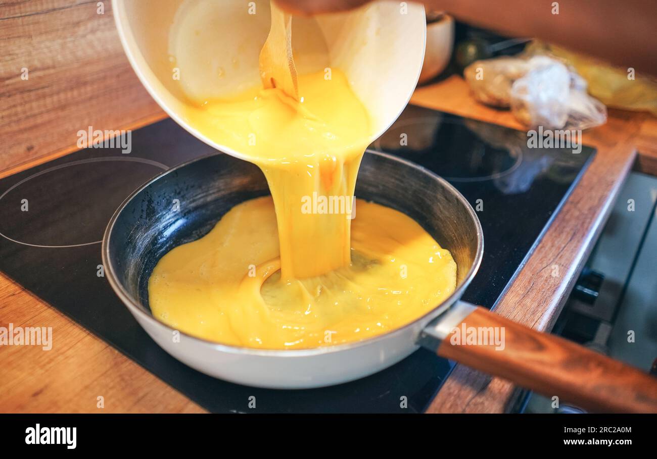 Scrambled eggs. Chef pouring liquid eggs on a hot pan. Making scrambled ...