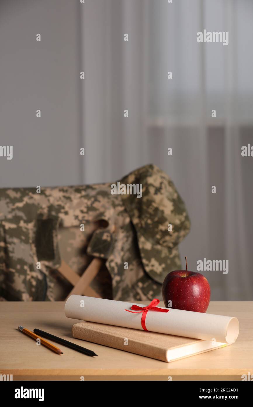 Diploma, apple and stationery on wooden table indoors. Military ...